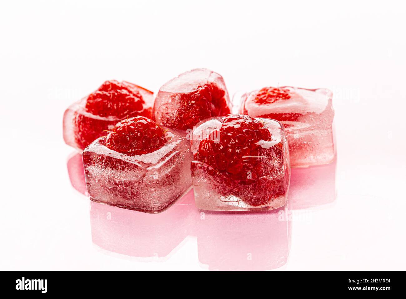Raspberry ice cubes on pink glossy background Stock Photo - Alamy