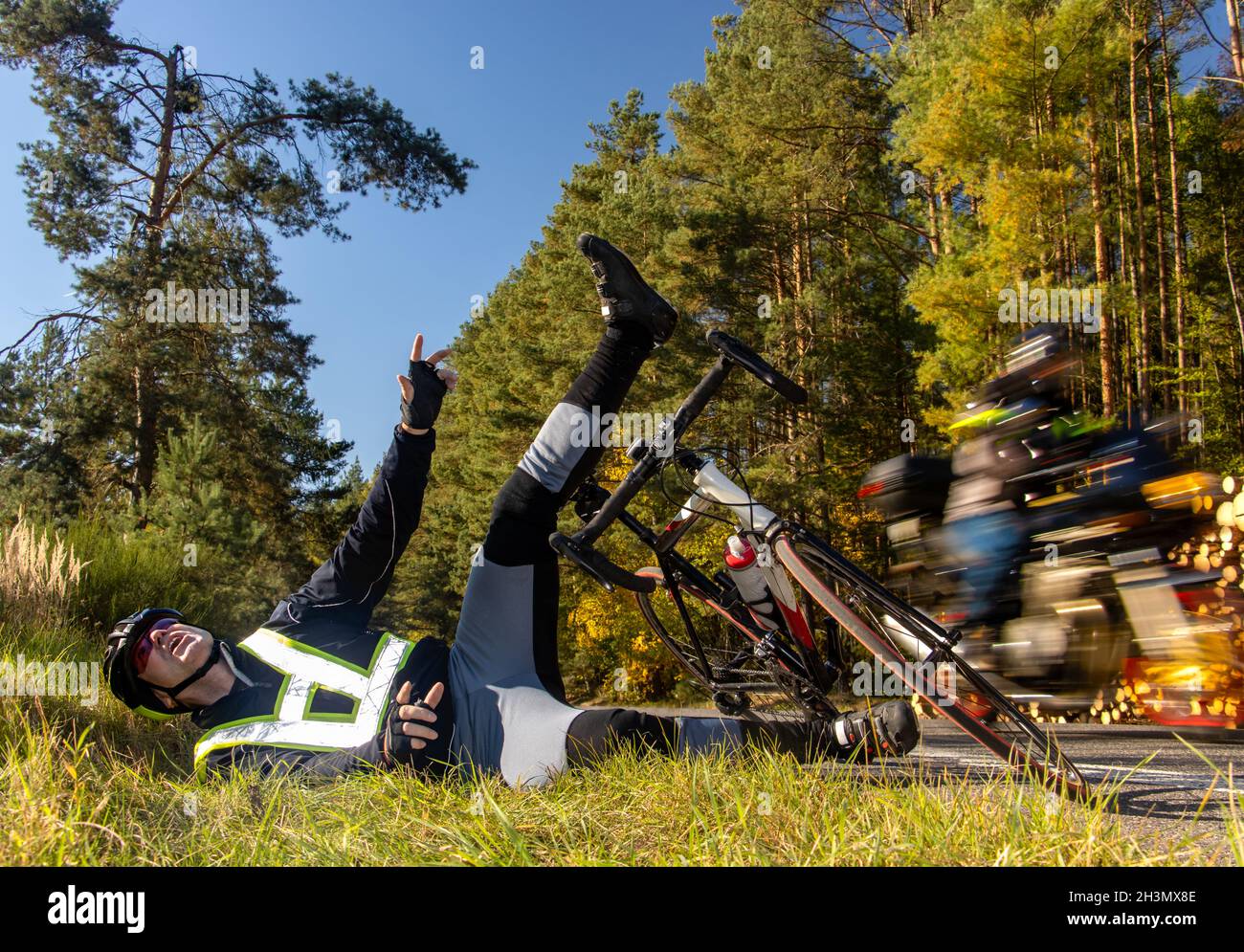 A fast-moving motorbike close passes a cyclist who falls to a ground ...