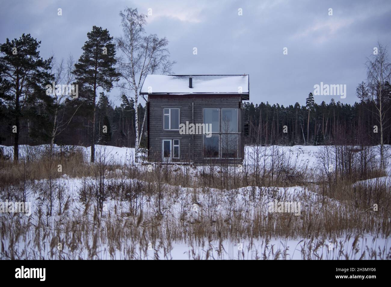 Front view of a farm building on a winter day with a forest in the ...
