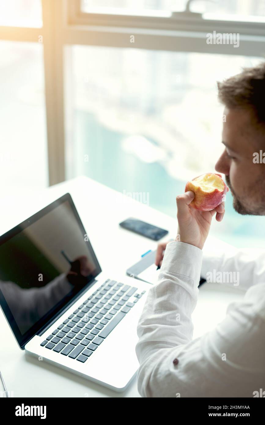 Employee having a healthy snack during work on lap top computer ...