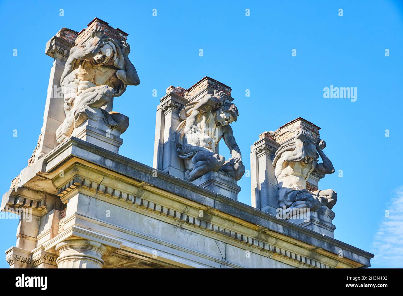 Three sculptures of men at top of old ruins against blue sky Stock ...