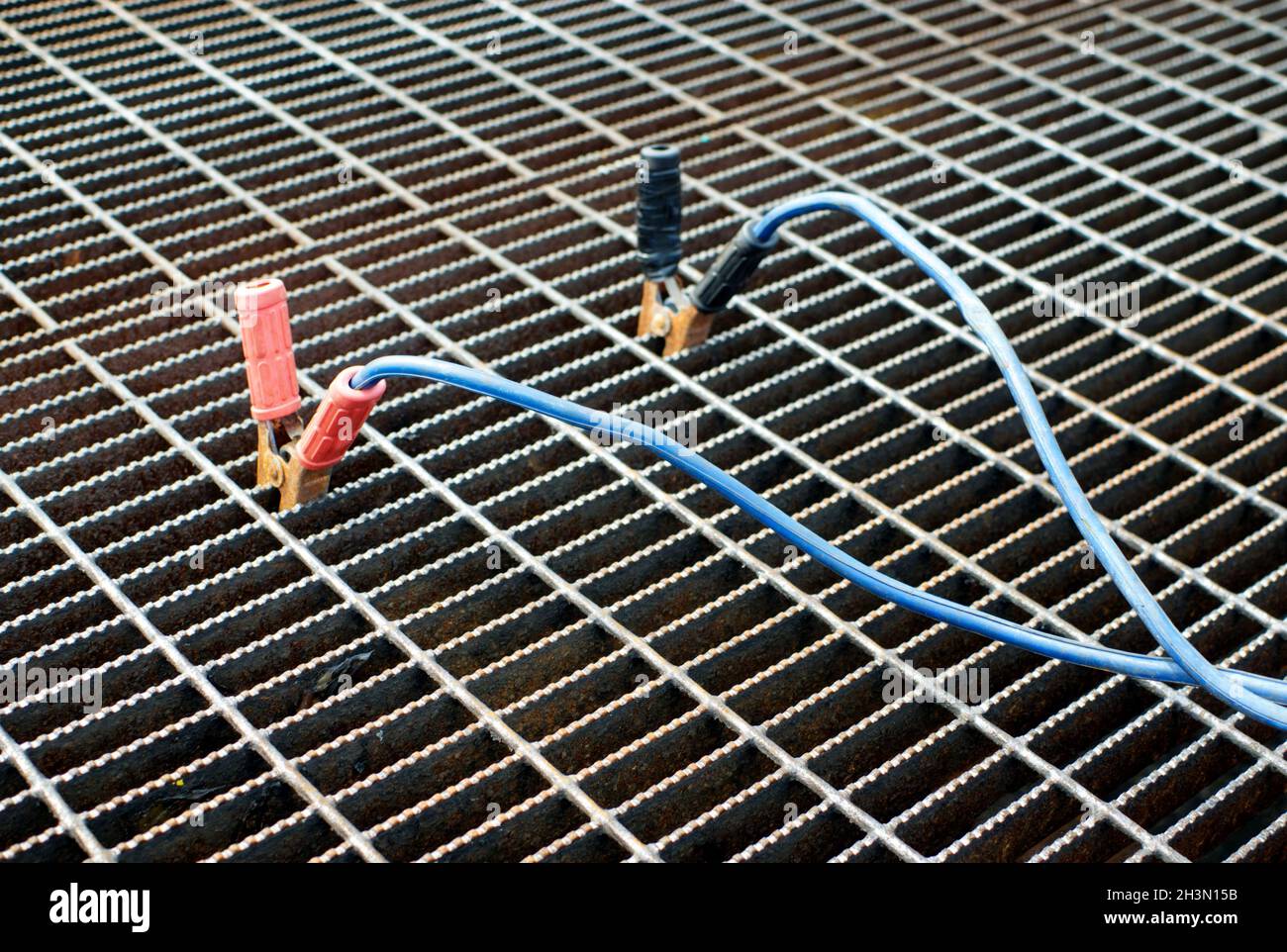 Jumper cables clamped to a metal grill Stock Photo - Alamy