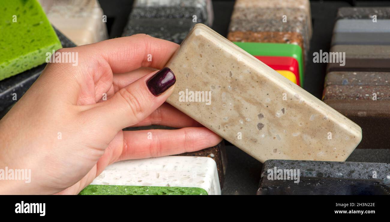 A woman chooses stone samples for a kitchen countertop. A set of multi ...