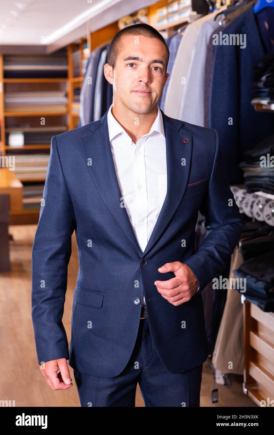 Positive male customer choosing fashion suit in mens store Stock Photo ...