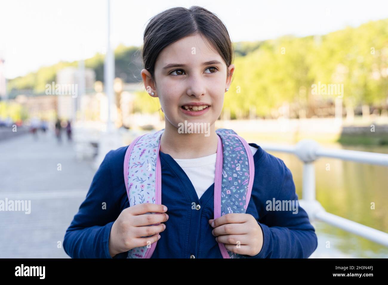 Portrait of little girl smiling looking to the side with school ...