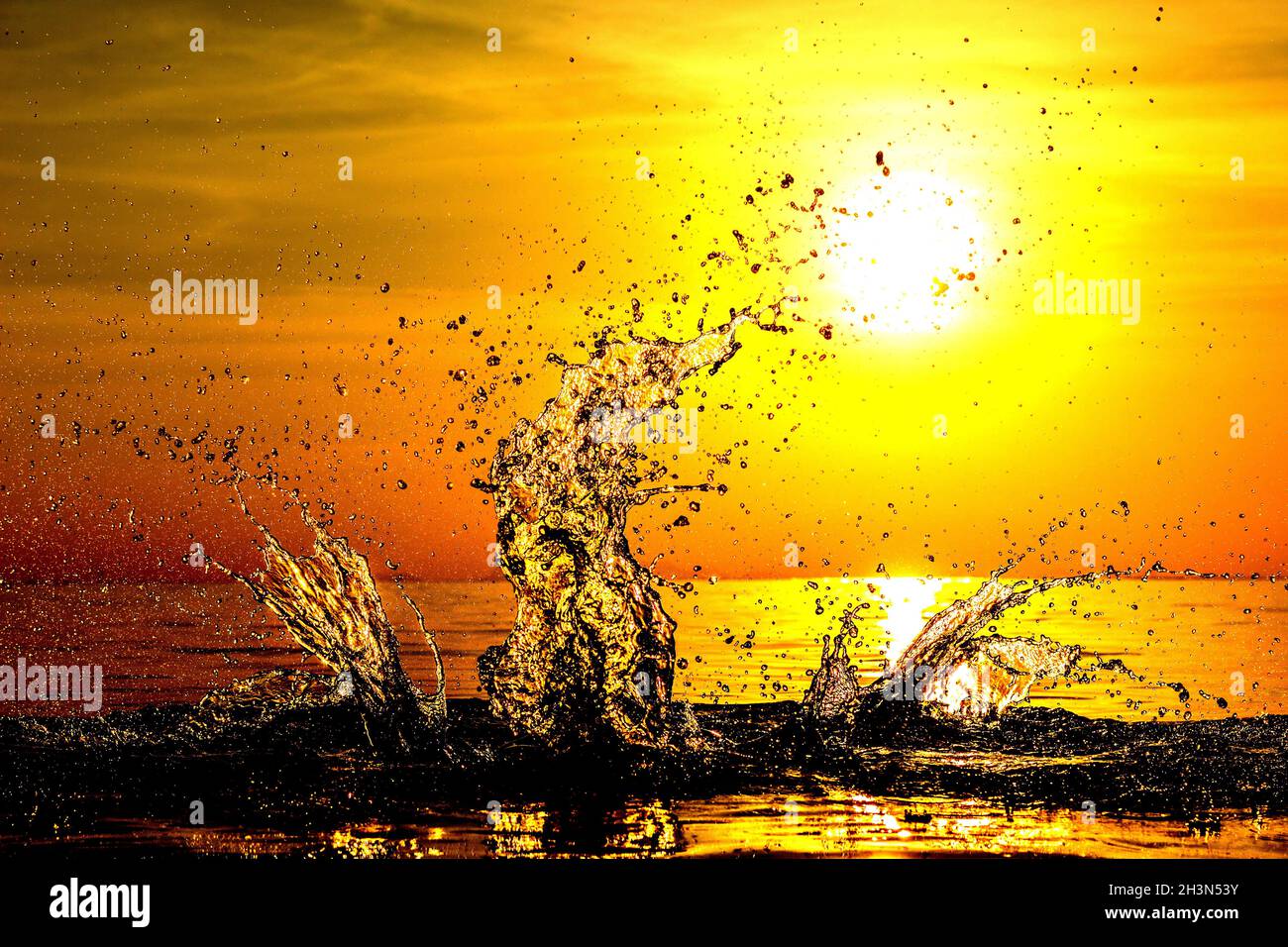 Water splash at sunset with intense orange and yellow light at freeze ...