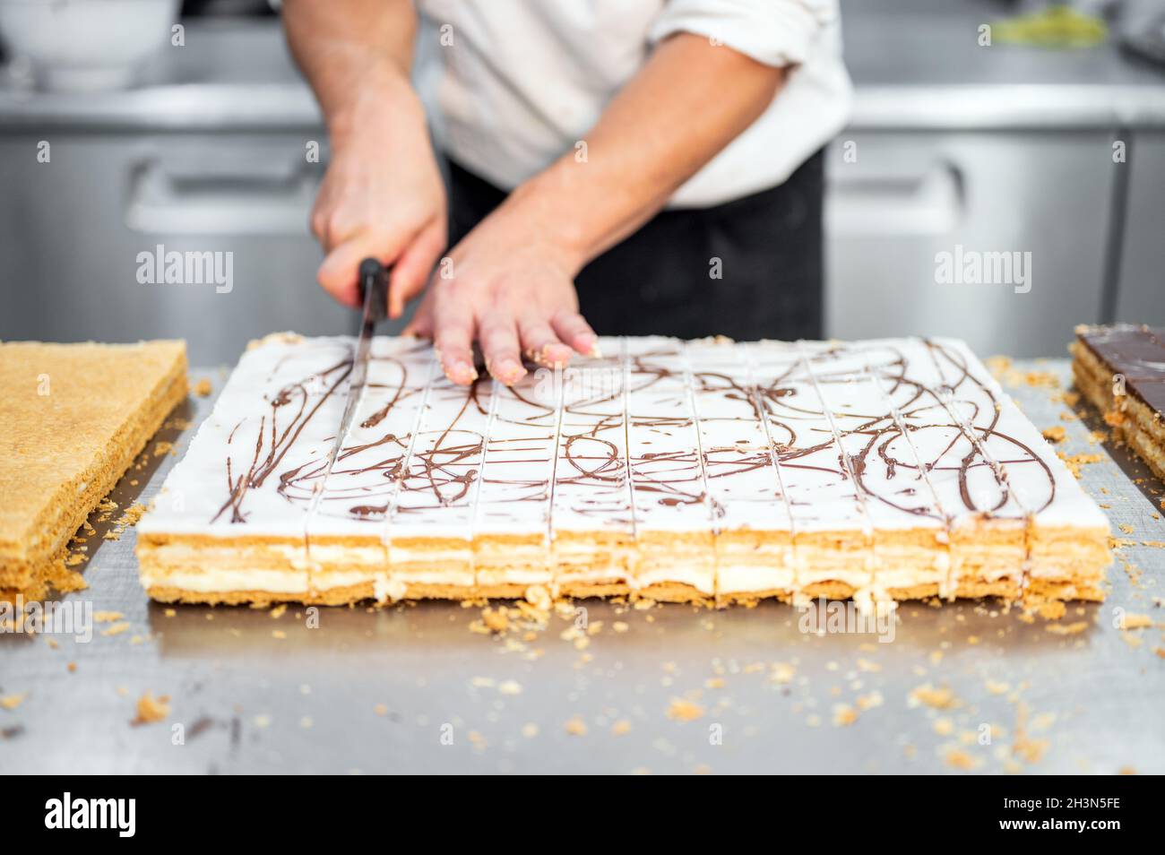 Close-up of a pastry chef cutting a large cake in portions at pastry ...