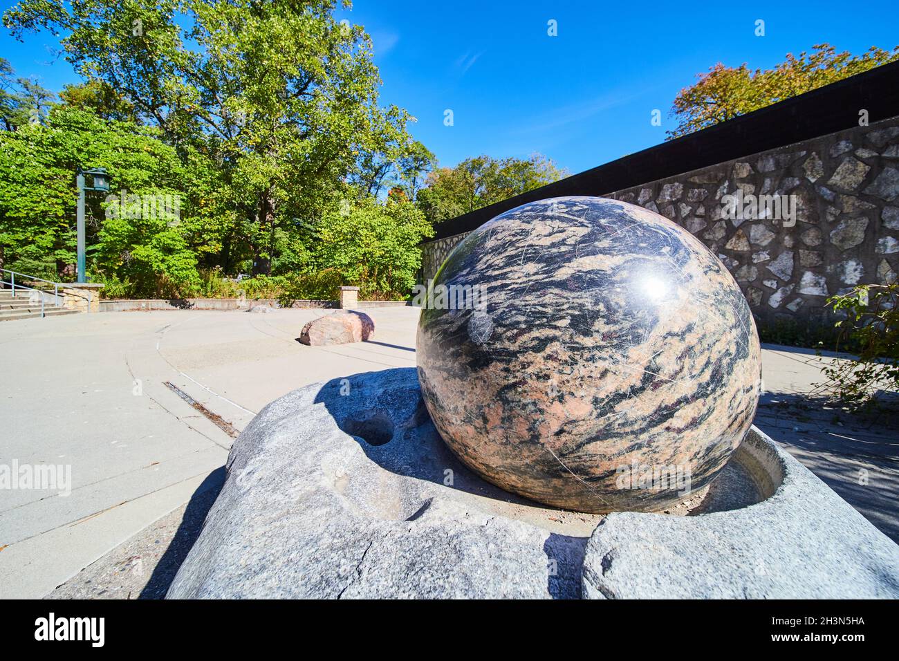 Large smooth marble sphere art set in rough stone of walking area Stock ...