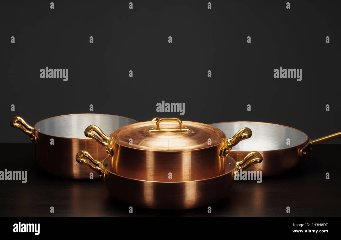 Shiny vintage copper cookware over dark background Stock Photo - Alamy