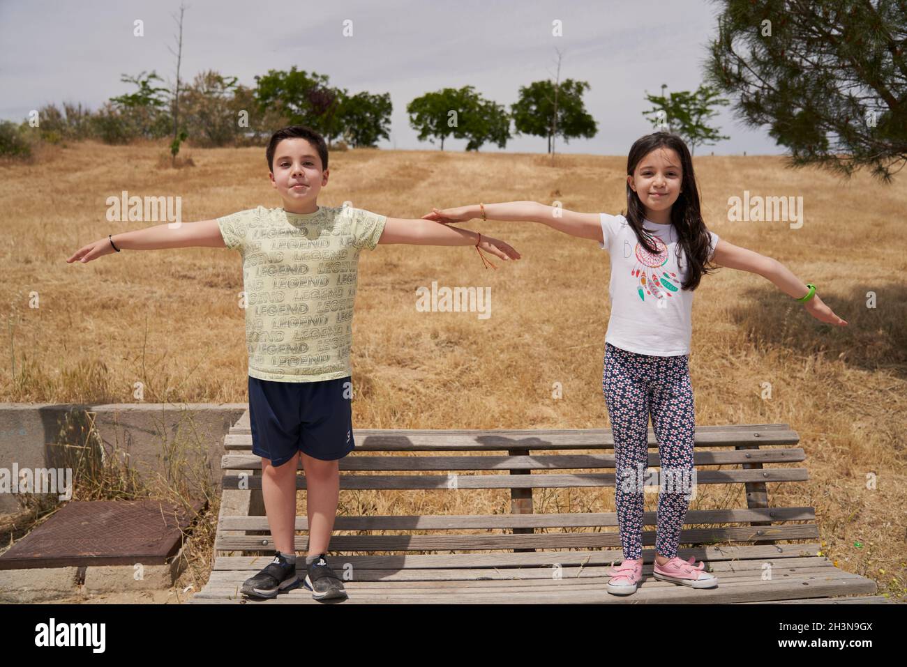 Happy children playing laughing up on wooden bench with arms crossed in ...
