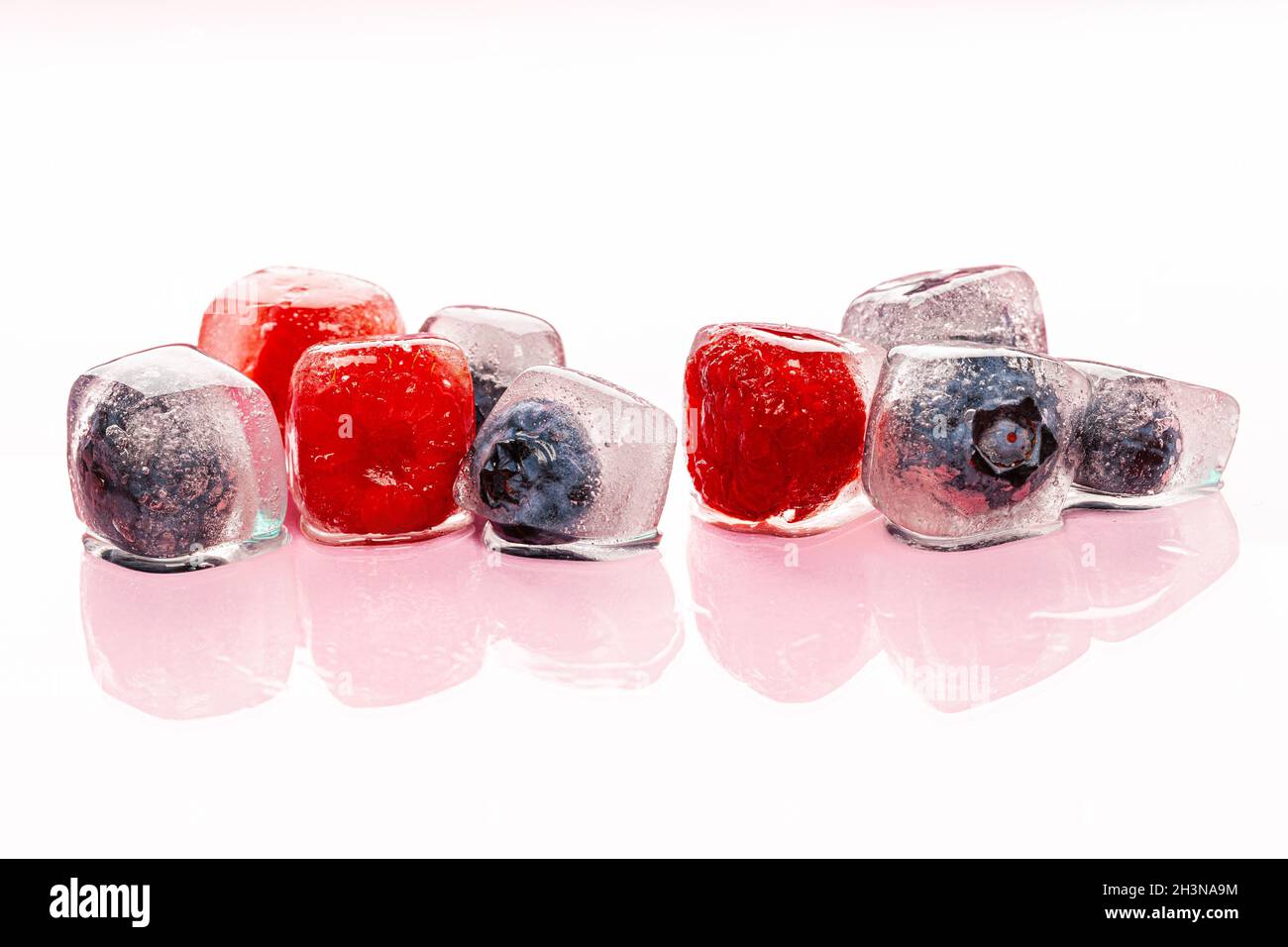 Fresh berries frozen in ice cubes for drinks Stock Photo - Alamy