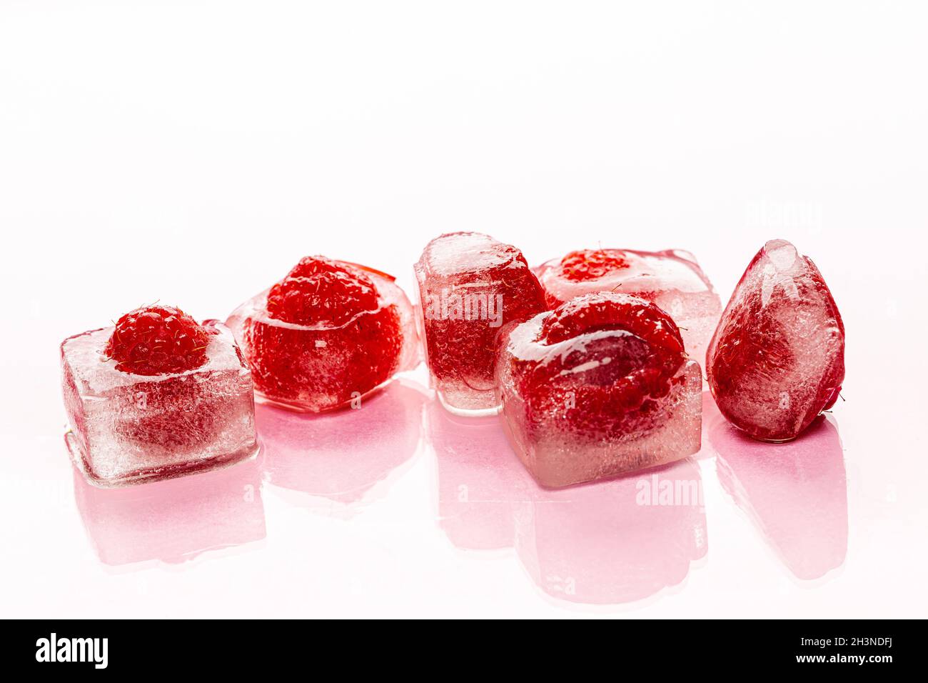 Raspberry ice cubes on pink glossy background Stock Photo - Alamy