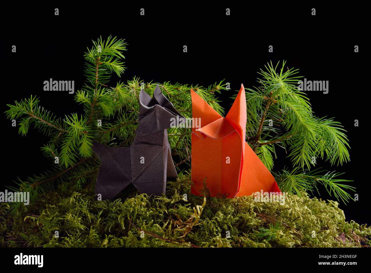 Origami paper wolf and fox on green moss isolated over black background ...
