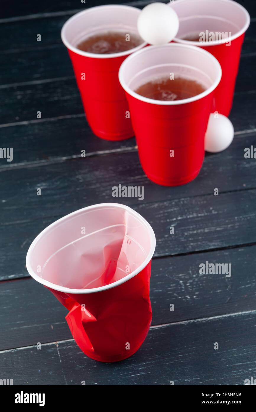 Wooden table with red cups and ball for beer pong Stock Photo - Alamy