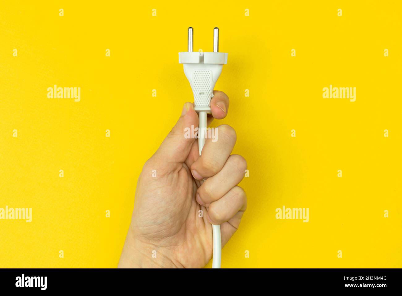Hand with electrical power cable. Yellow background, flat lay, top view ...