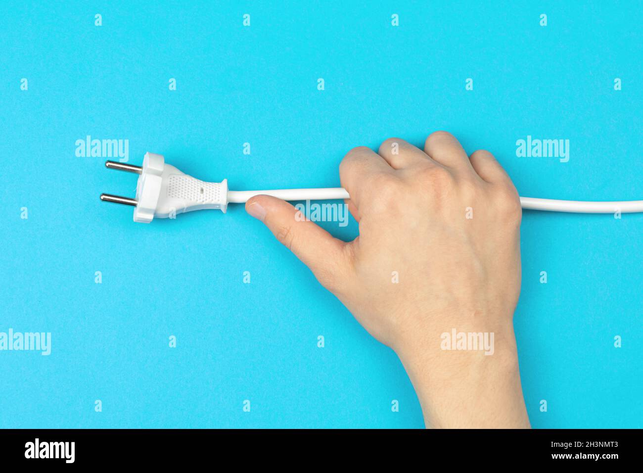 Hand with electrical power cable with EU plug on a bright blue ...