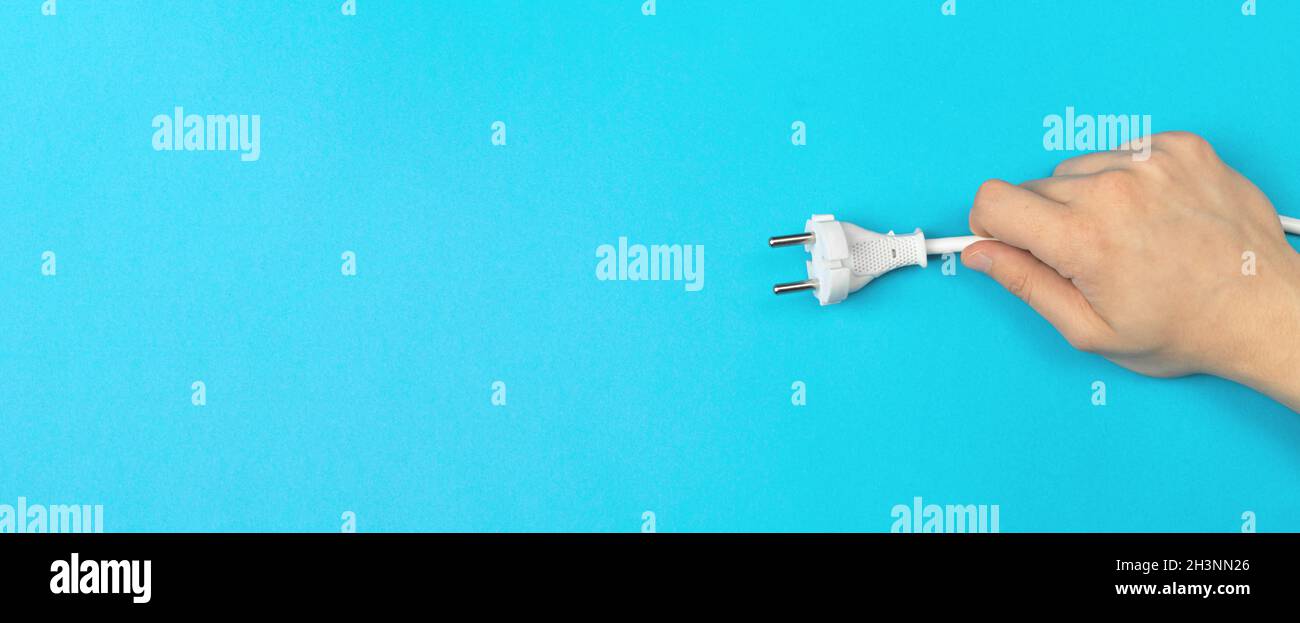 Hand use power cable with EU plug on a bright blue background, banner ...