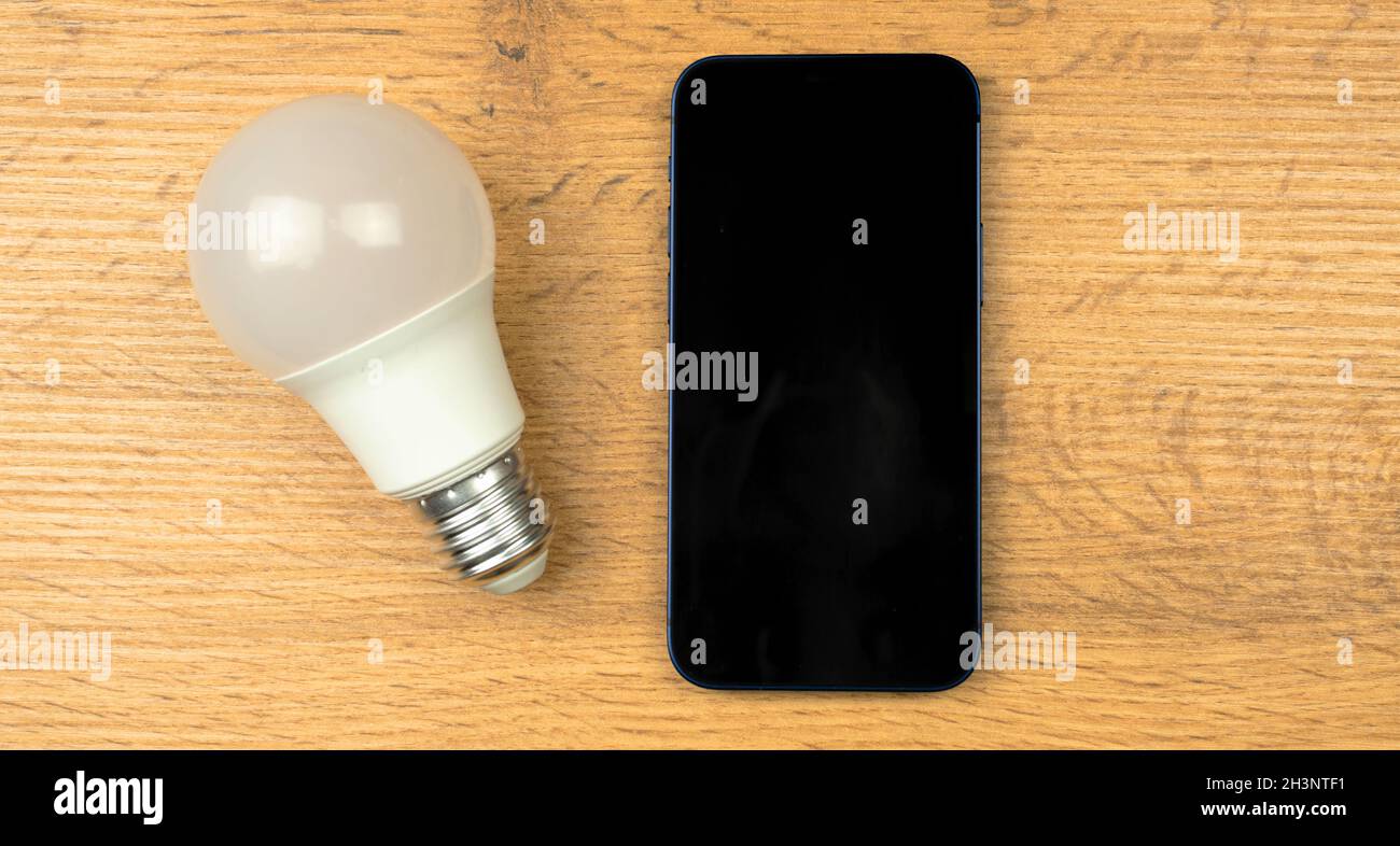 Light bulb power concept. Mobile phone on a wooden table, top view ...