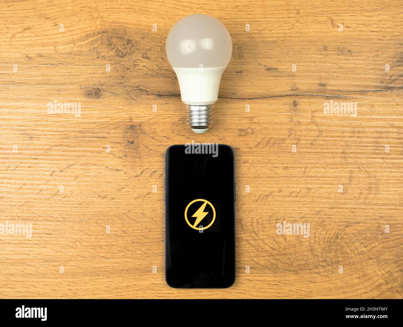 LED light bulb and mobile phone on a wooden table. Energy saving ...