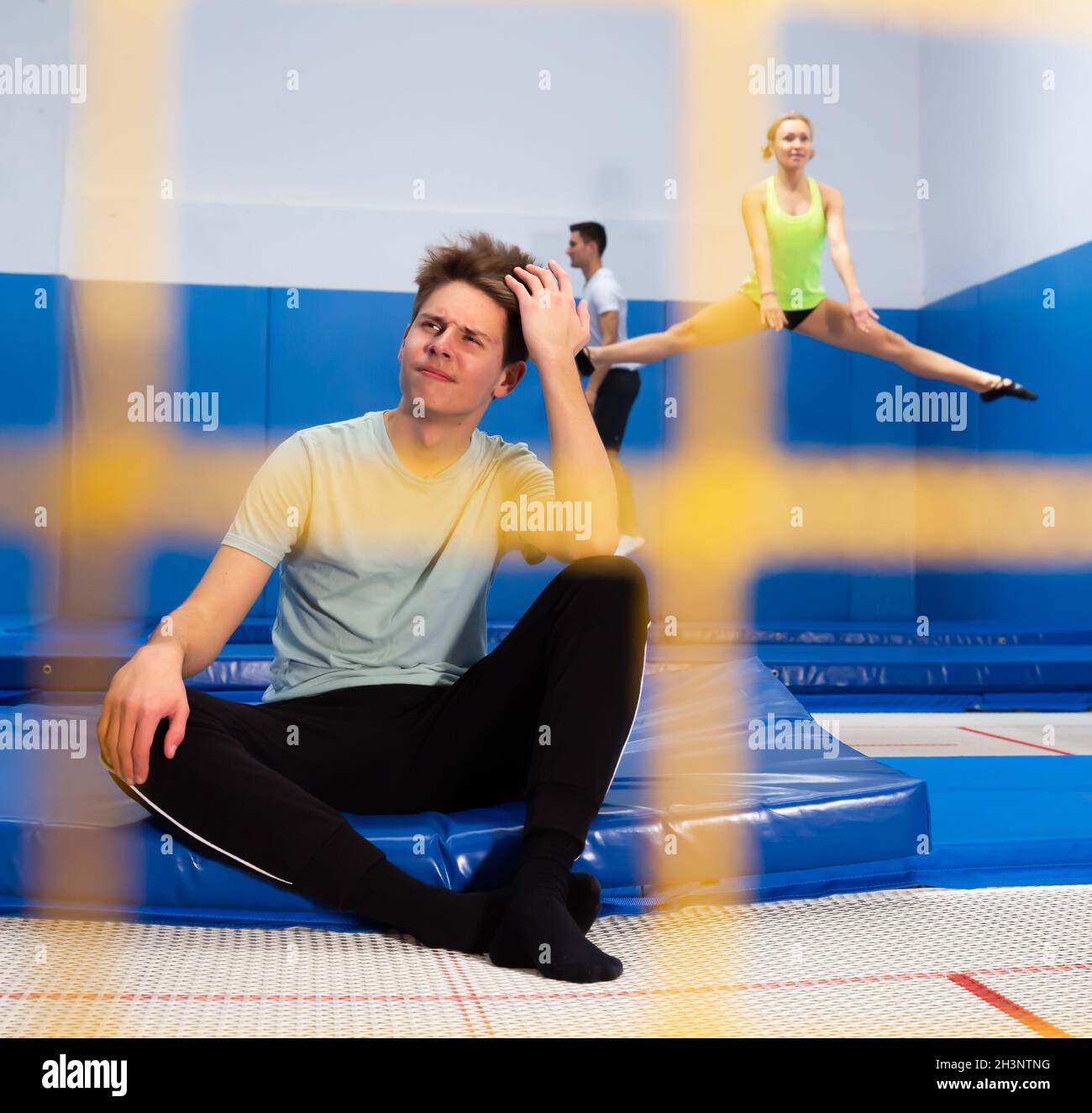 Tired teenage guy resting after trampoline training Stock Photo - Alamy