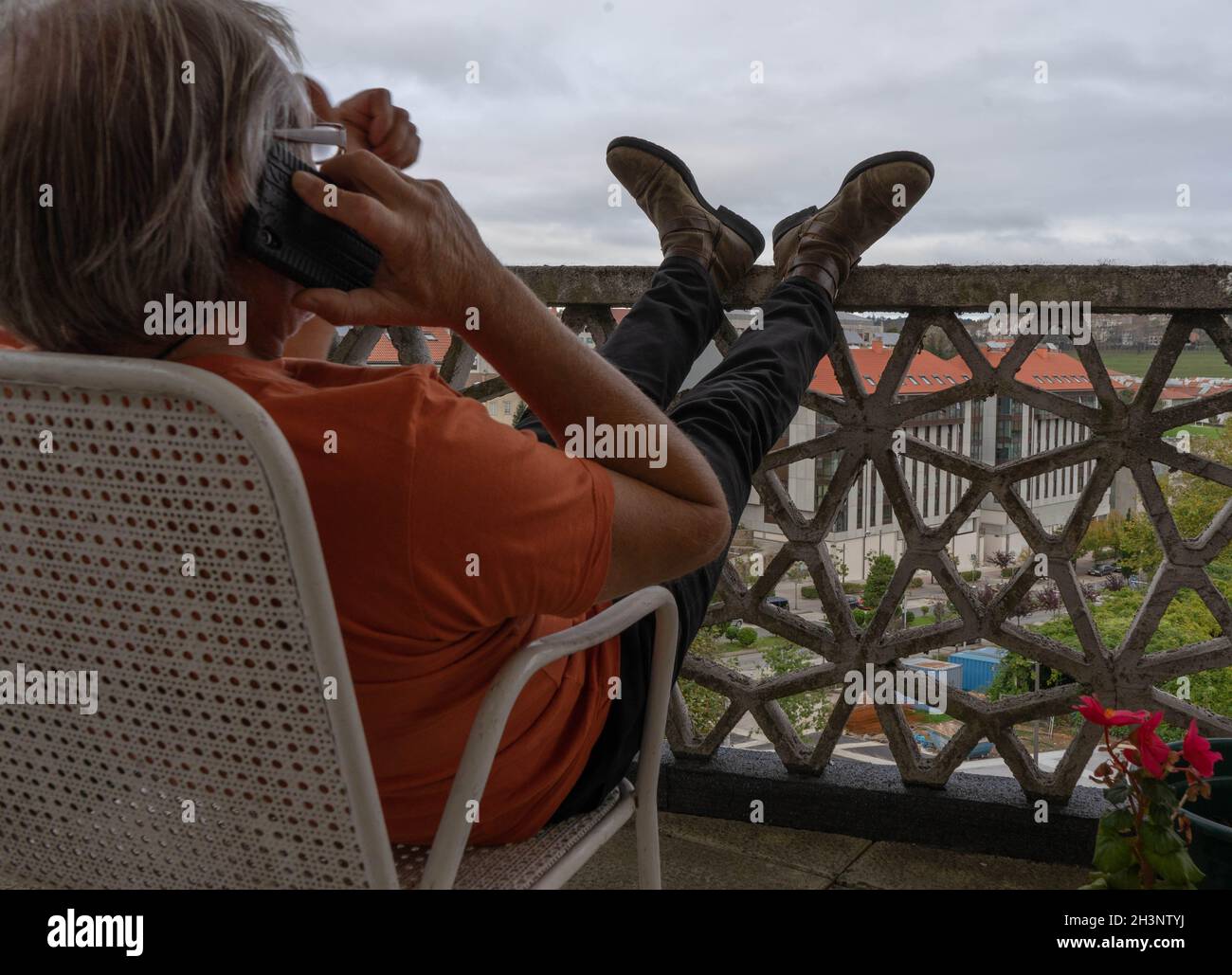 middle-aged man talking on the phone on a terrace with his feet up on ...