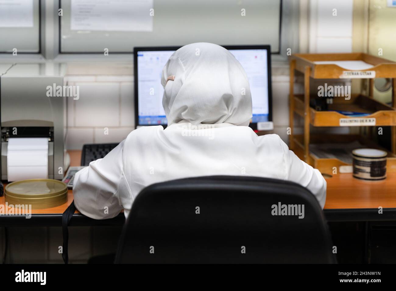 Anonymous person on white protective uniform sitting in office in front ...