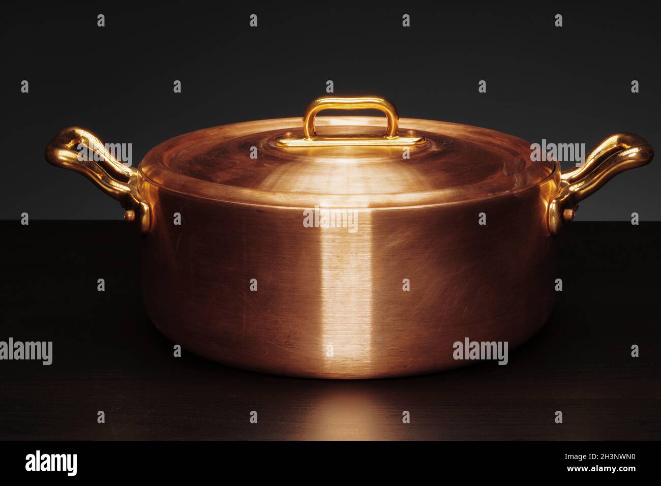 Shiny vintage copper cookware over dark background Stock Photo - Alamy
