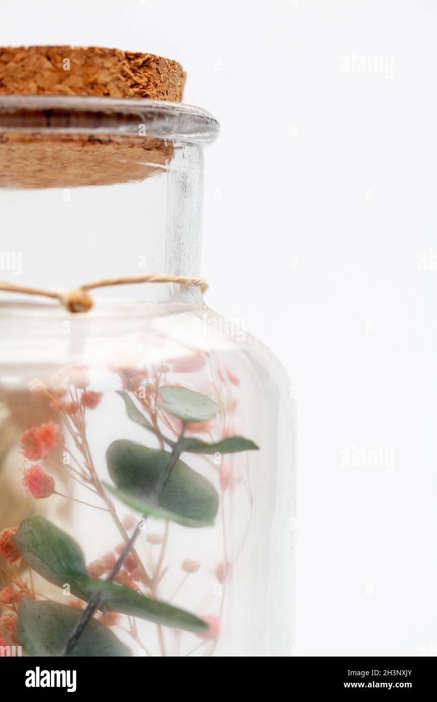 Bouquet of dry flowers and potpourri in a glass jar on a white table ...