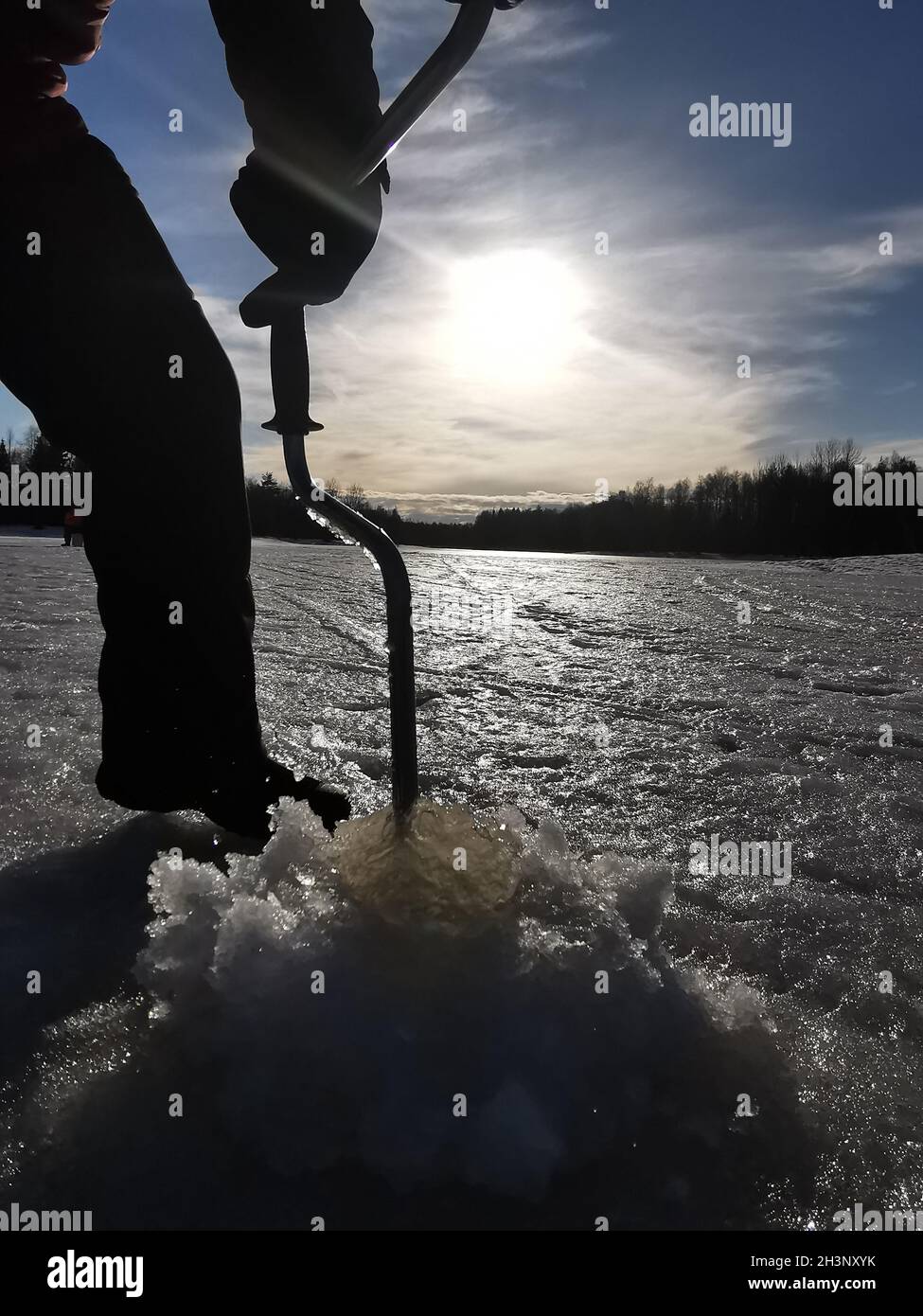 Drilling a hole into the thick ice for fishing in Finland Stock Photo ...