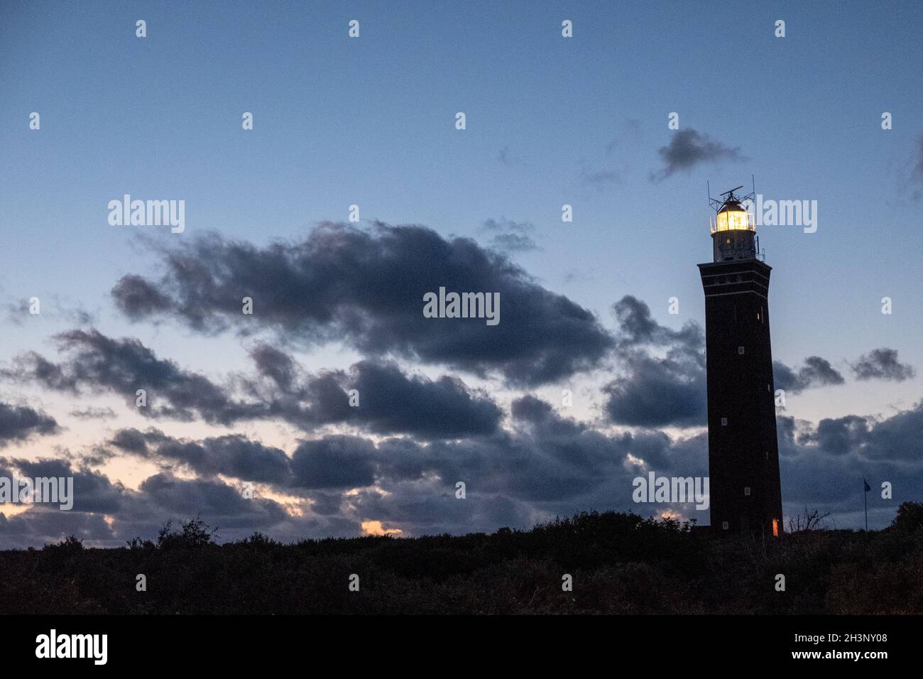 Lighthouse standing on the Dutch coast with a dramatic. and colorful ...