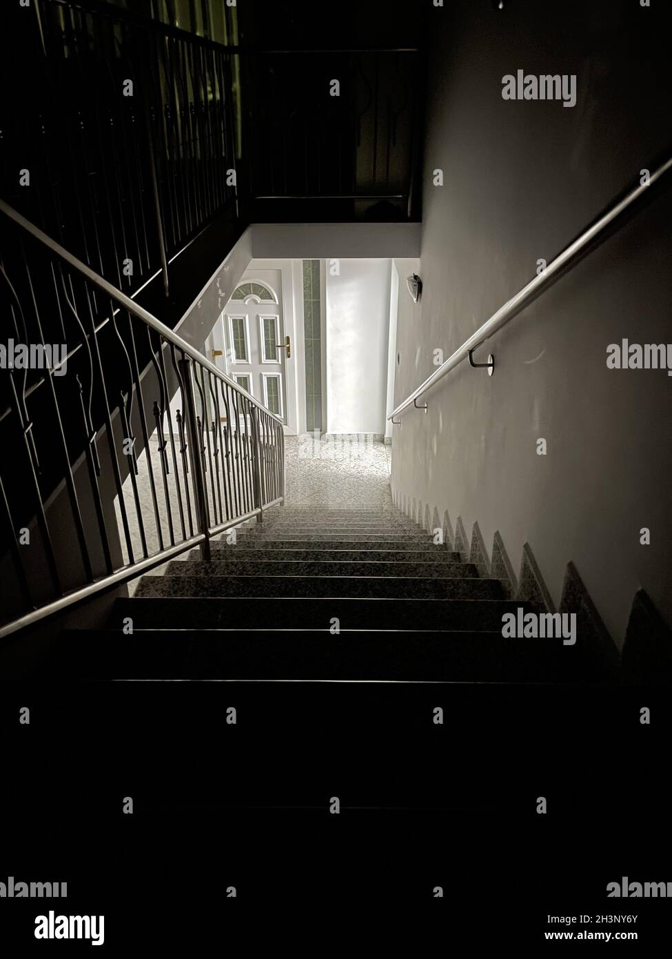 Vertical shot of stairs going down to the hall with a white wooden door ...