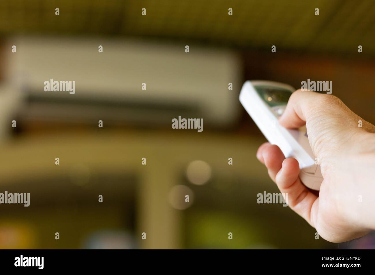 Close up of hand with remote control pointing at AC unit. Air ...