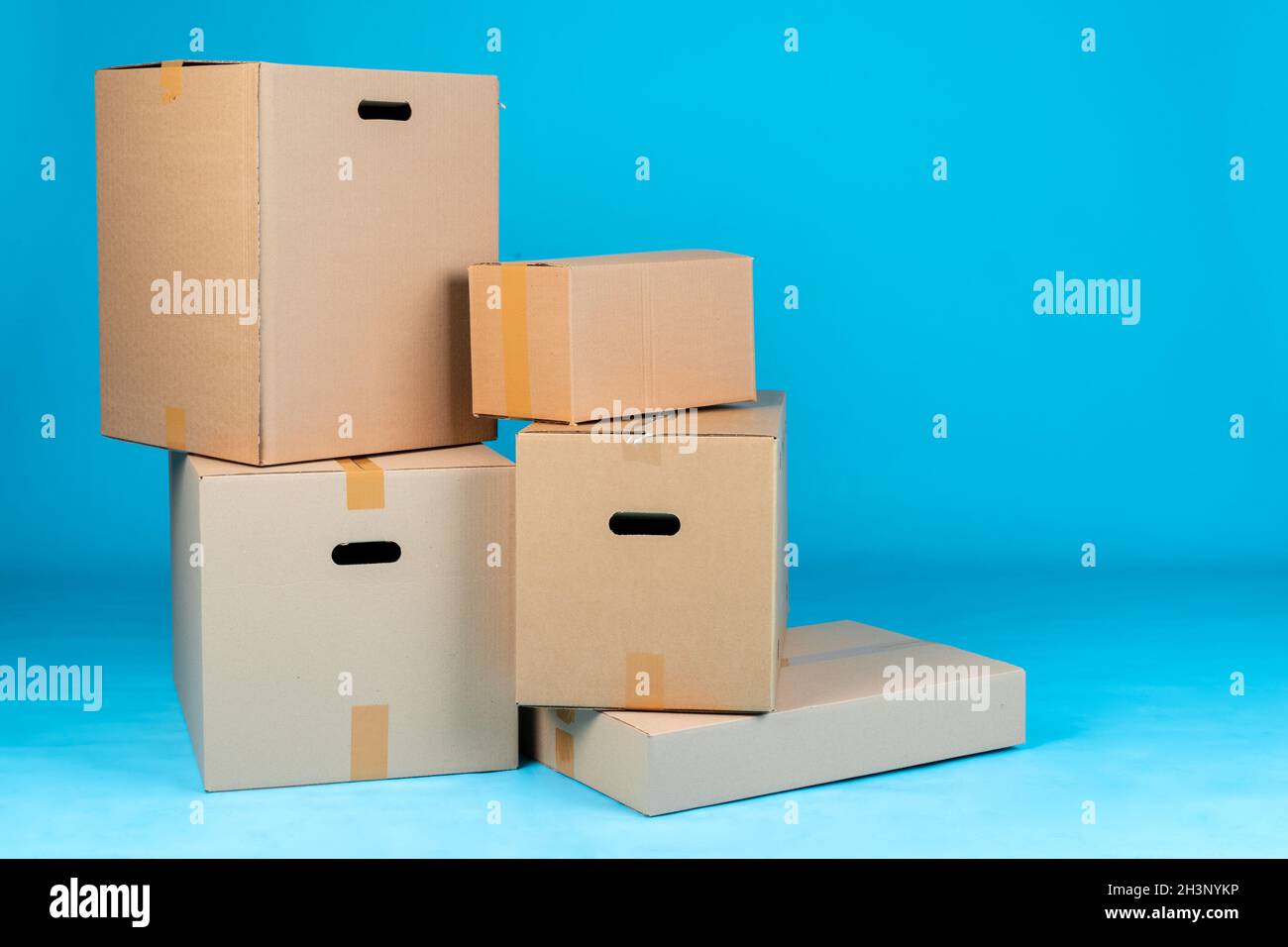 Stack of cardboard boxes on blue background Stock Photo - Alamy