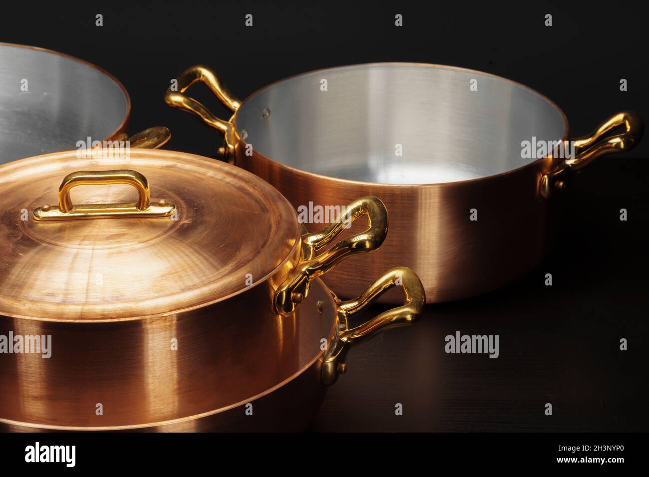 Shiny vintage copper cookware over dark background Stock Photo - Alamy