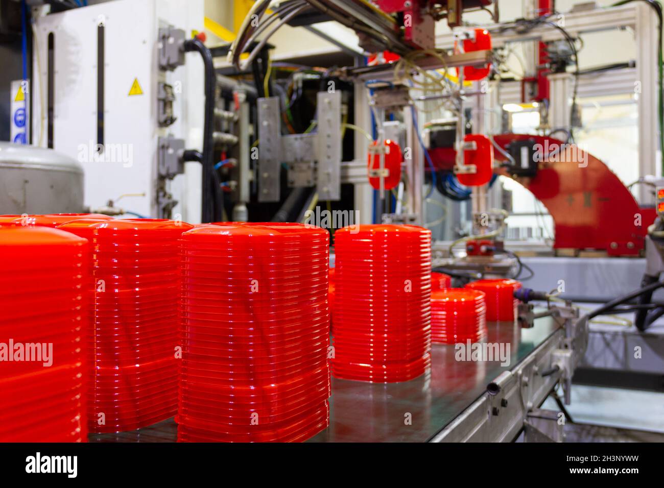 Factory machine placing red plastic lids on conveyor belt. Industrial ...