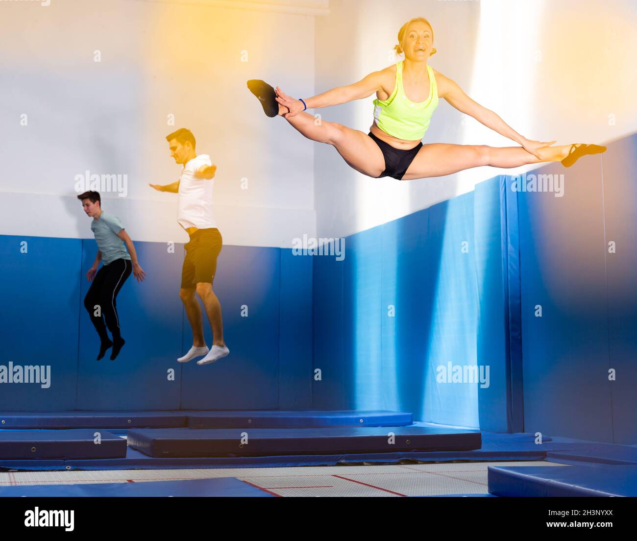 Female gymnast practicing middle split on trampoline Stock Photo - Alamy