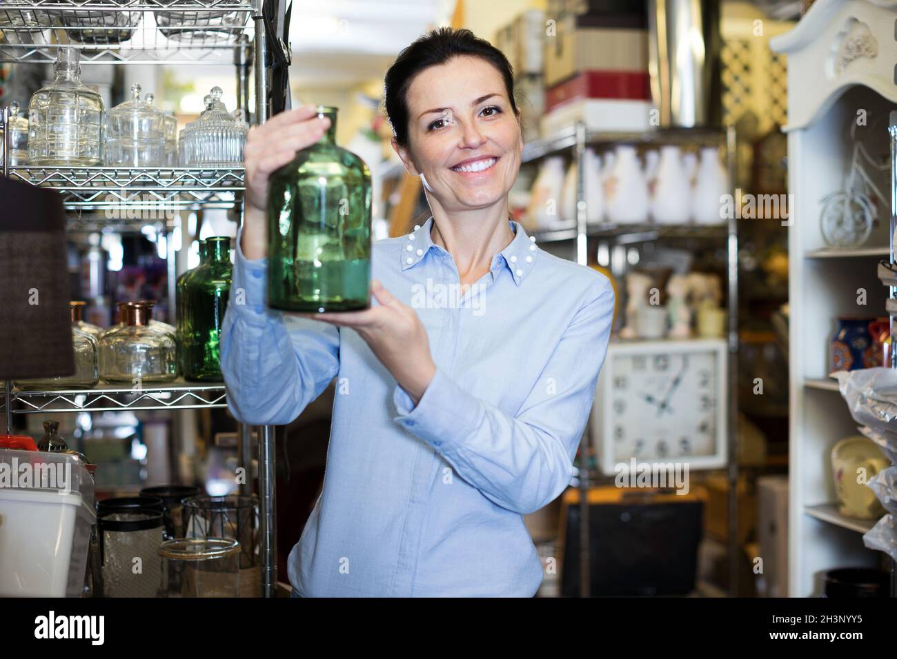 Positive female showing fragile glass item in store Stock Photo - Alamy