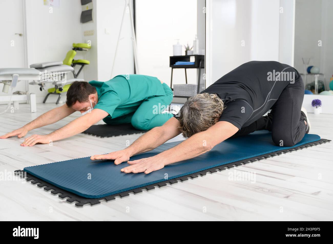 Therapist with protective face mask Assisting patient With Stretching ...