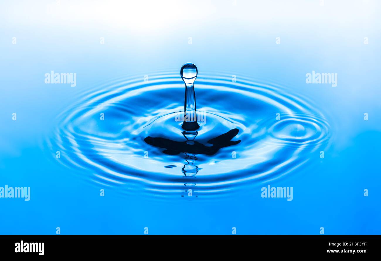 Water drop splashing into blue water surface. Health and purity concept ...