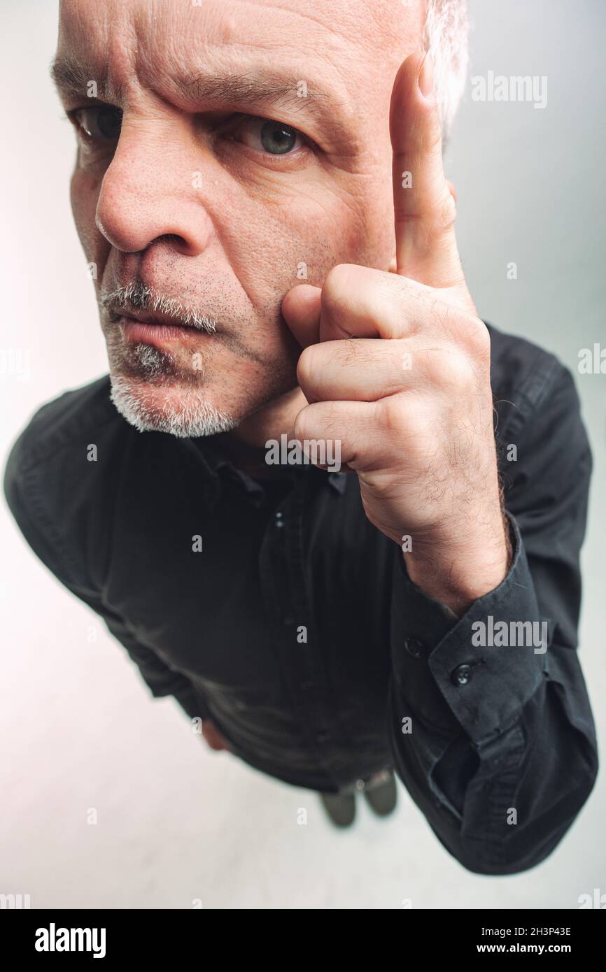 Dogmatic senior man making a point wagging his finger at the camera ...