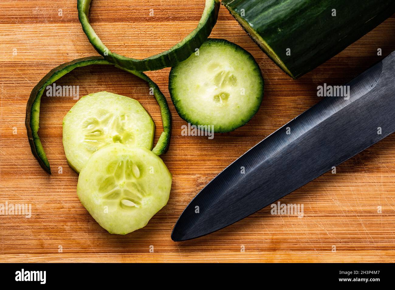 Cucumber sliced on wooden cutting board Stock Photo - Alamy