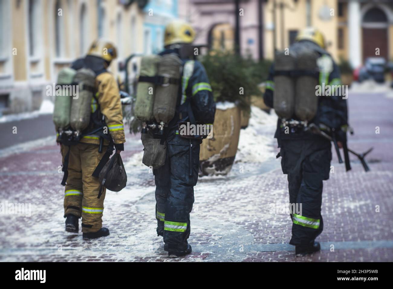 Group of fire men in uniform during fire fighting operation in the city ...