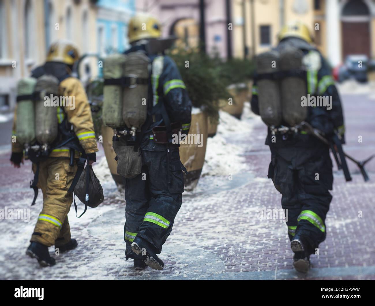 Group of fire men in uniform during fire fighting operation in the city ...