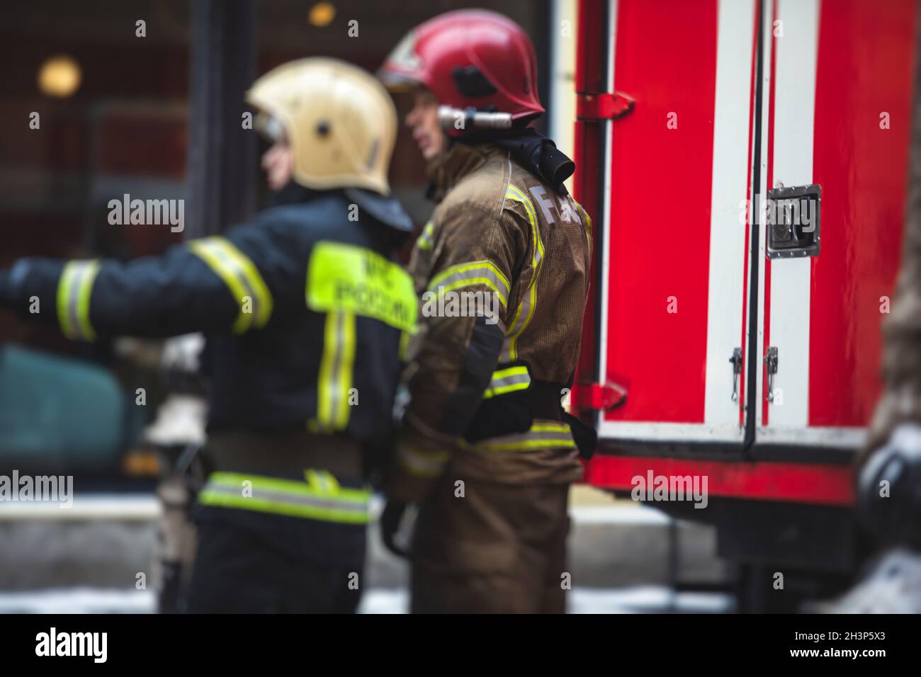Group of fire men in uniform during fire fighting operation in the city ...