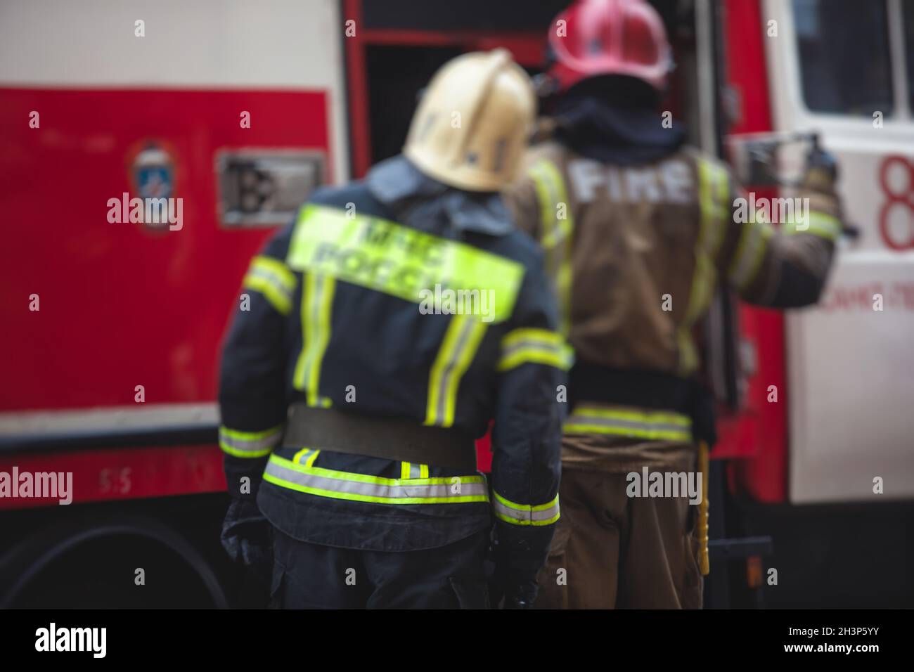 Group of fire men in uniform during fire fighting operation in the city ...
