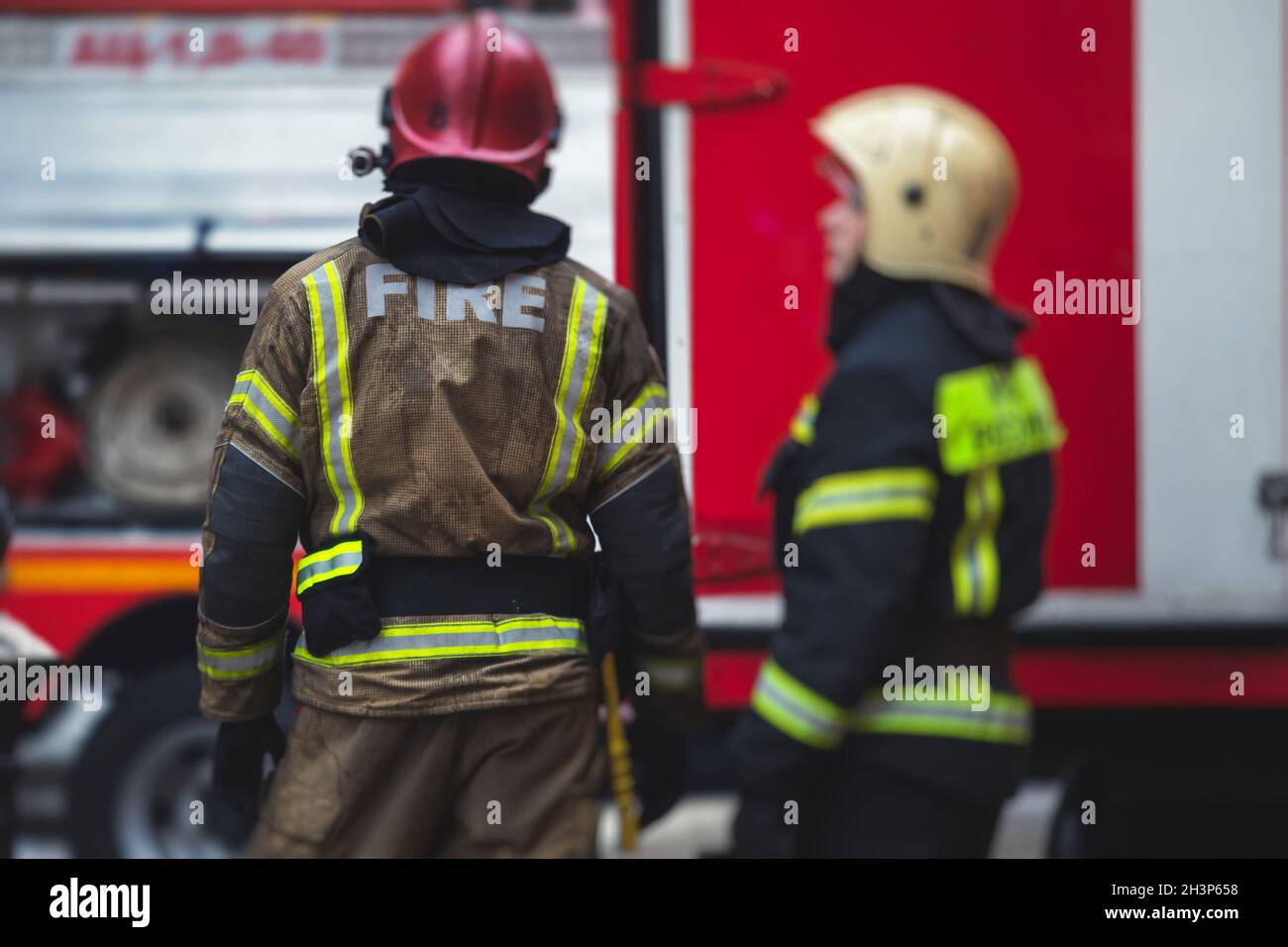 Group of fire men in uniform during fire fighting operation in the city ...