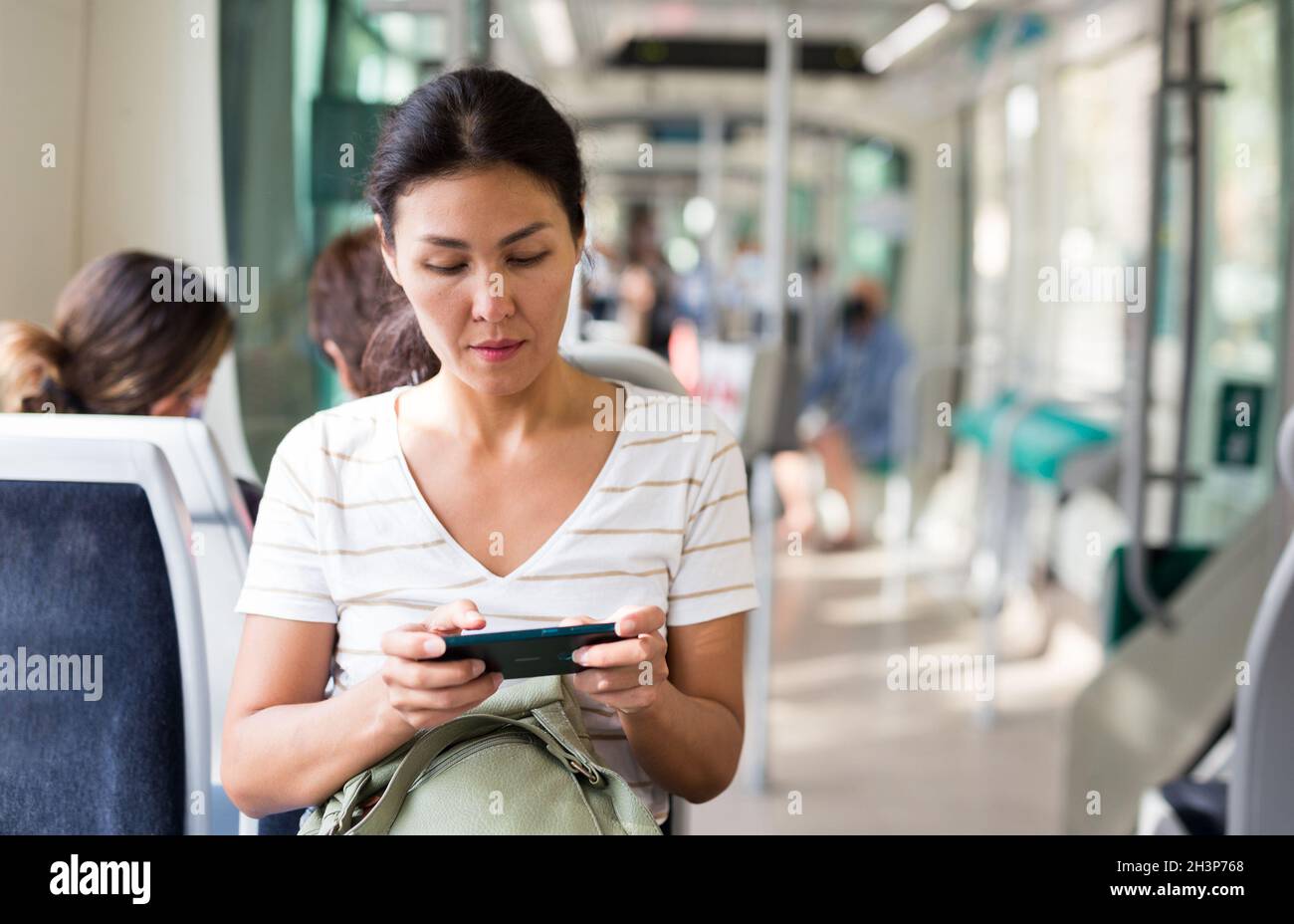 Woman with phone sitting inside tram Stock Photo - Alamy