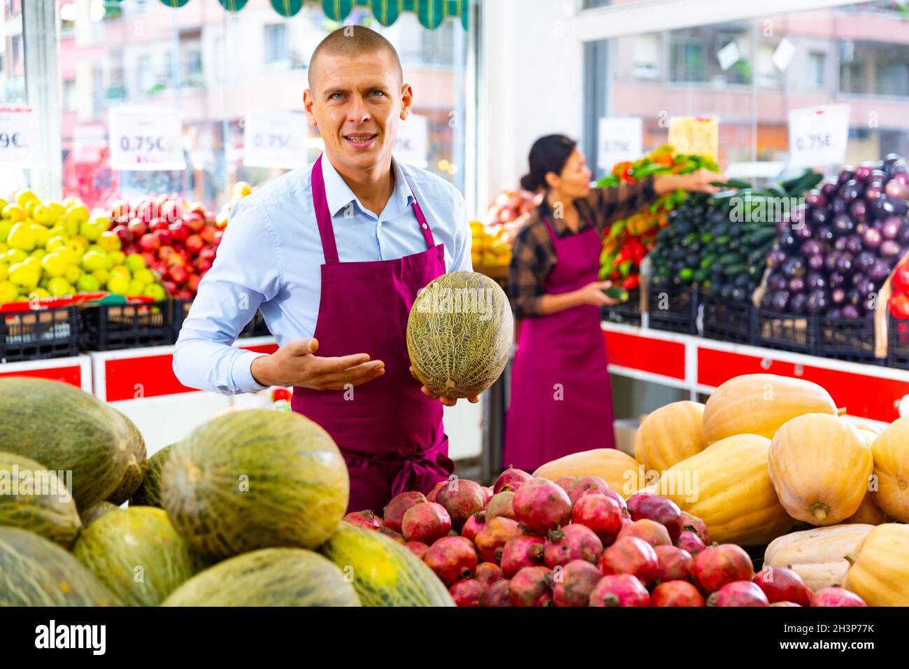 Salesman offering ripe melon in fruit and vegetable store Stock Photo ...