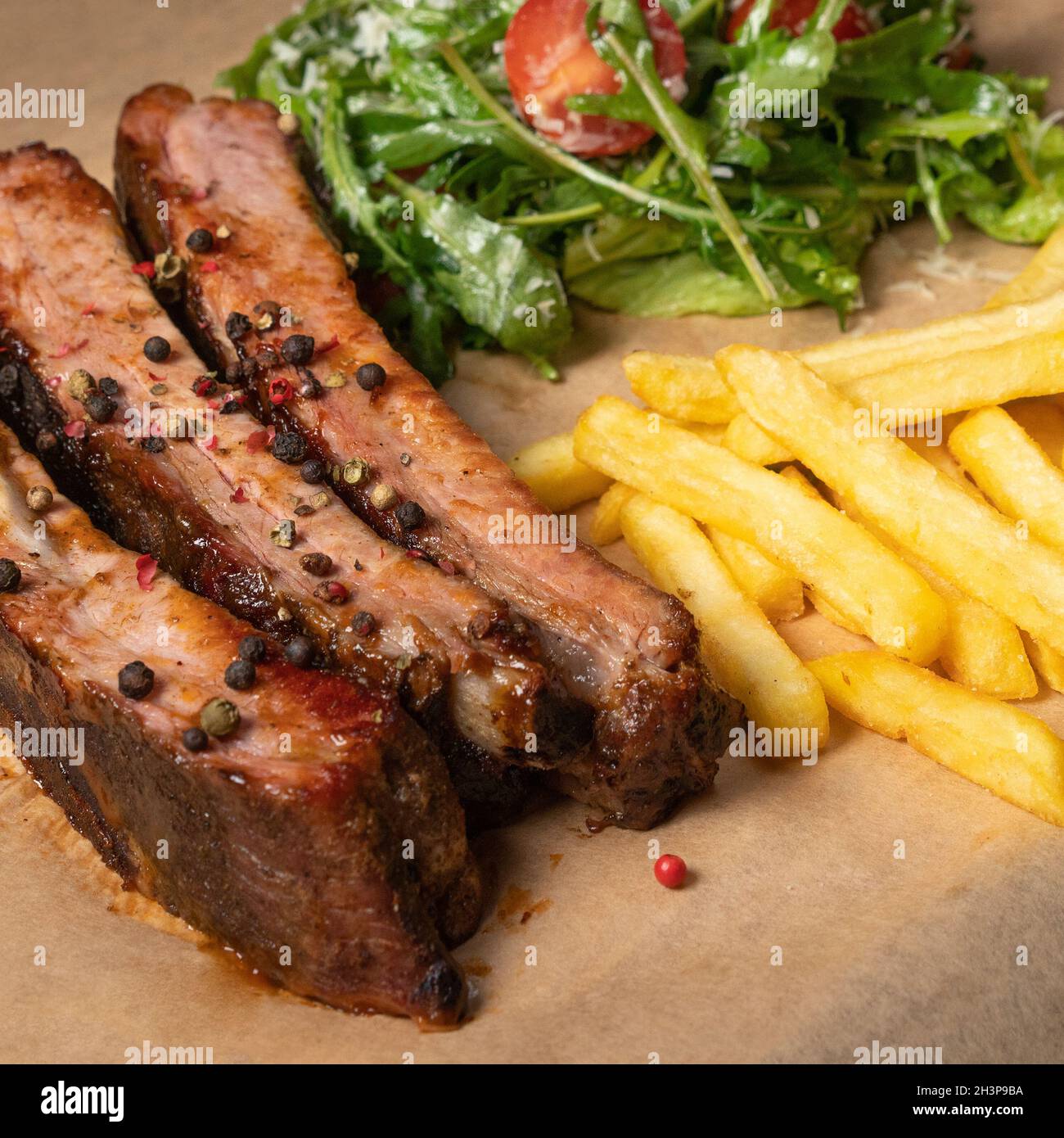 BBQ spare ribs served with French fries and arugula salad with cherry ...