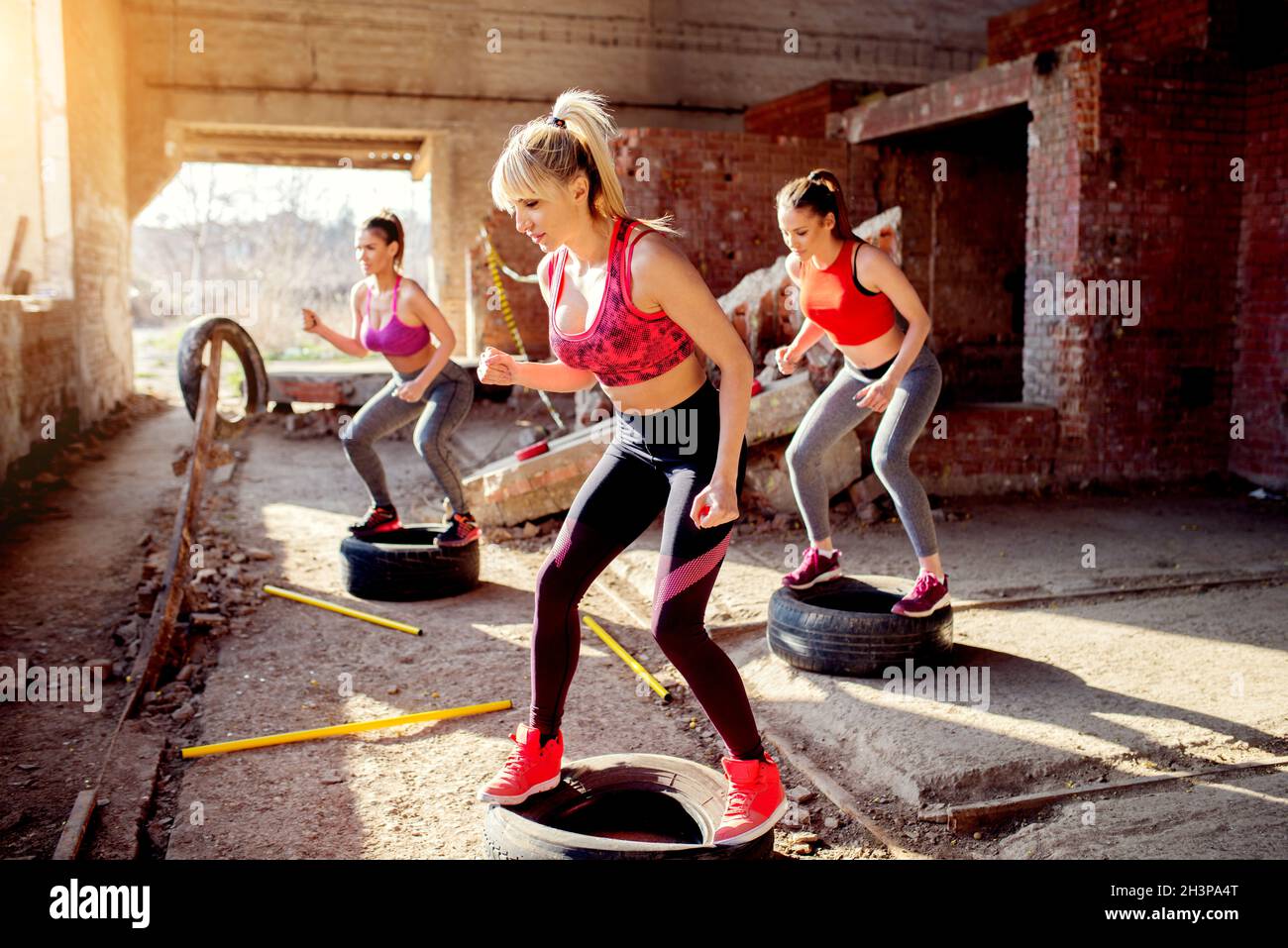 Working hard at abandoned factory. Group of fitness people doing squats ...